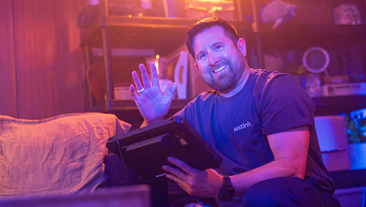 An Eastlink technician smiling and waving while he installs a customer ...